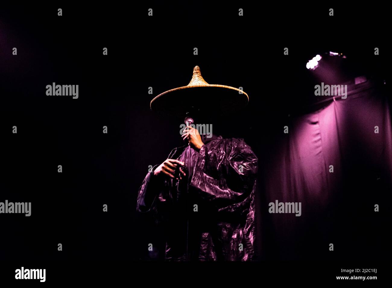 An African singer in an asian hat performing live on a stage with ...