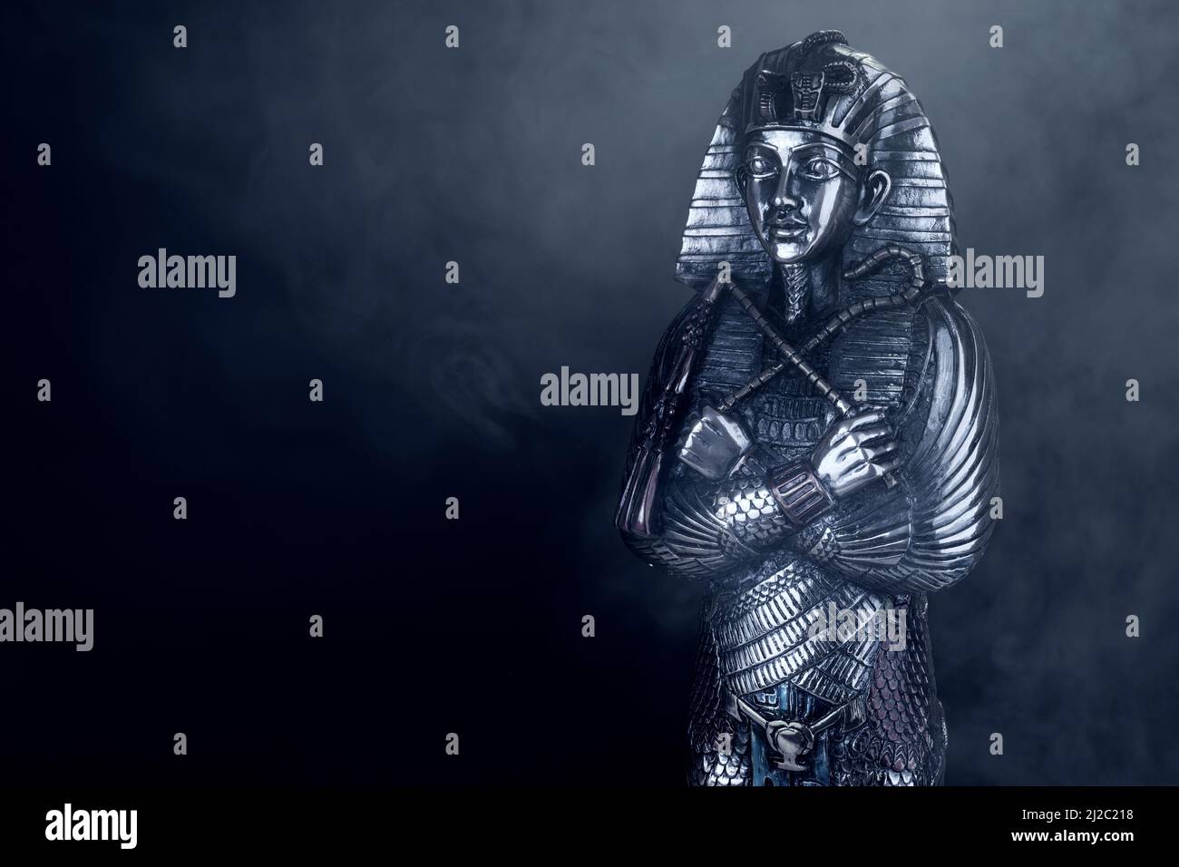 steel figurine of the pharaoh on a black background with smoke. High ...