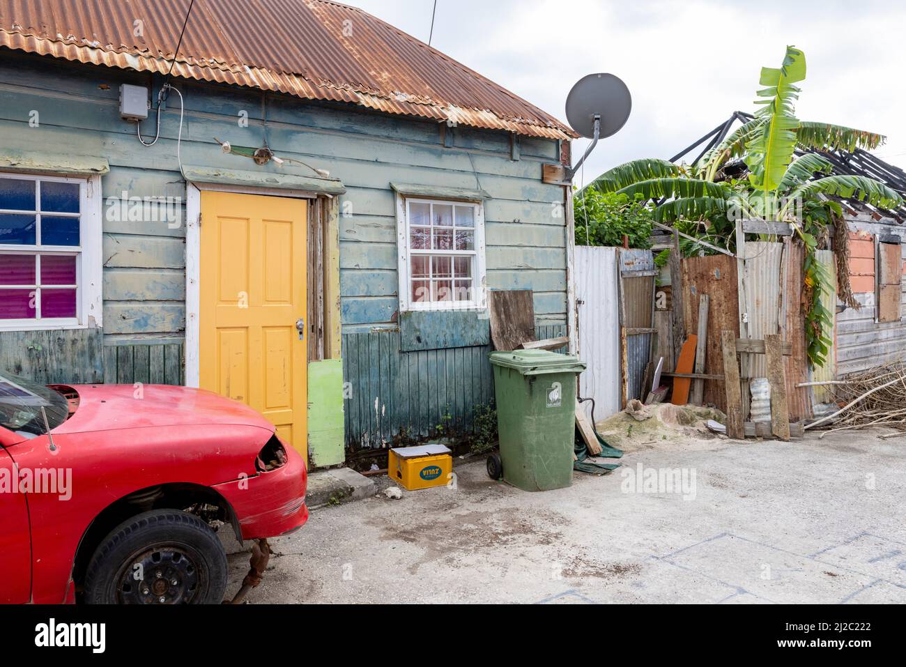 Side street with small weathered house and a broken red car in the ...