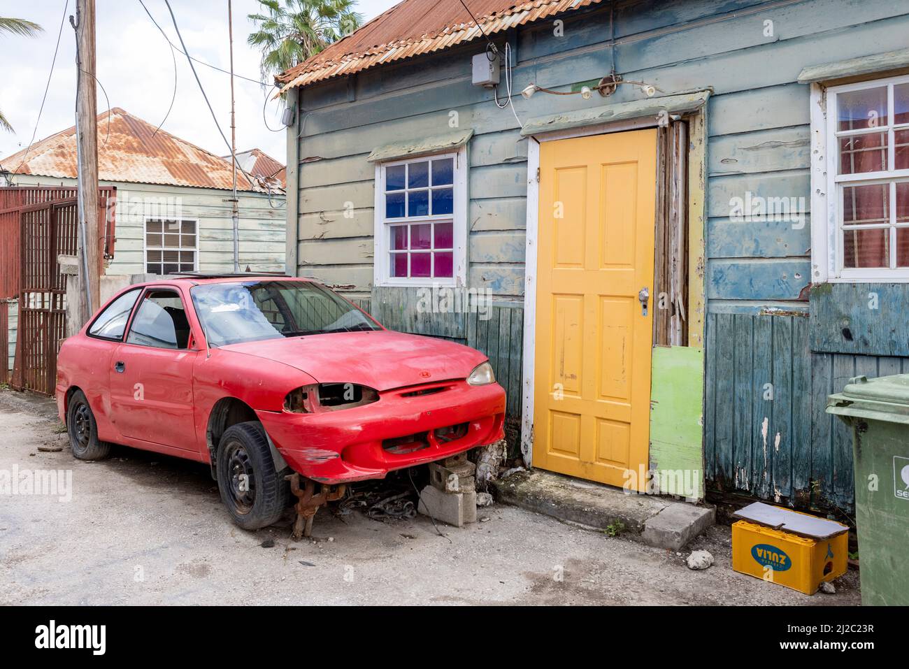 Side street with small weathered house and a broken red car in the ...