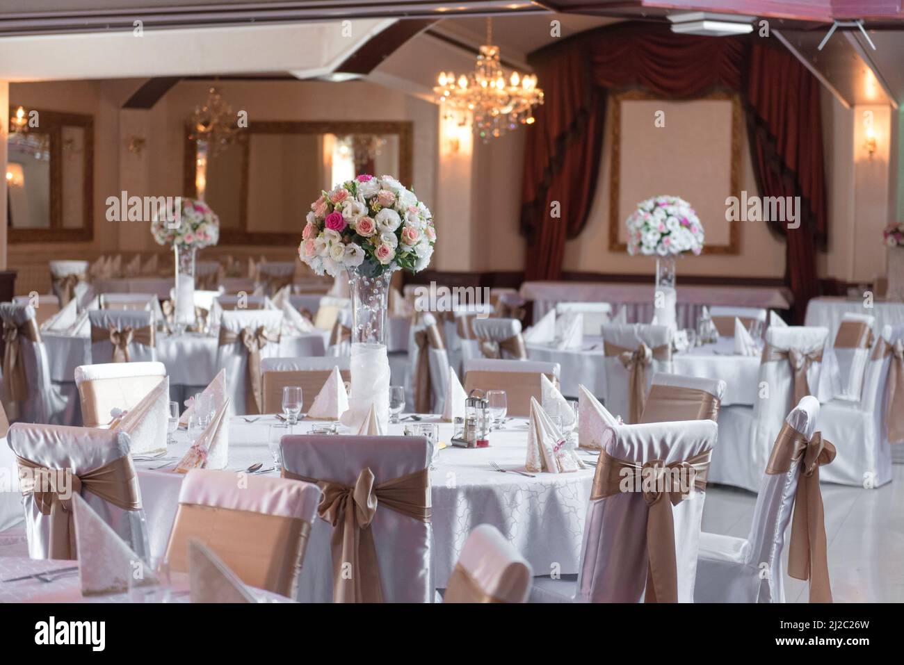 A view of an interior of a wedding hall with decorated tables and ...