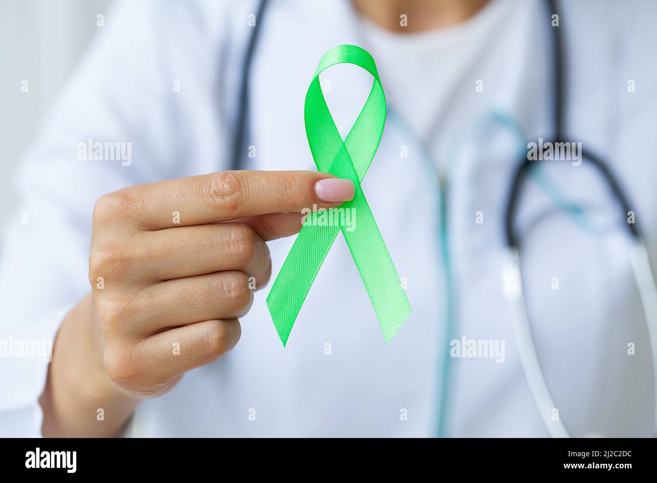 Doctor in uniform holds a green ribbon as a symbol of Lyme disease ...