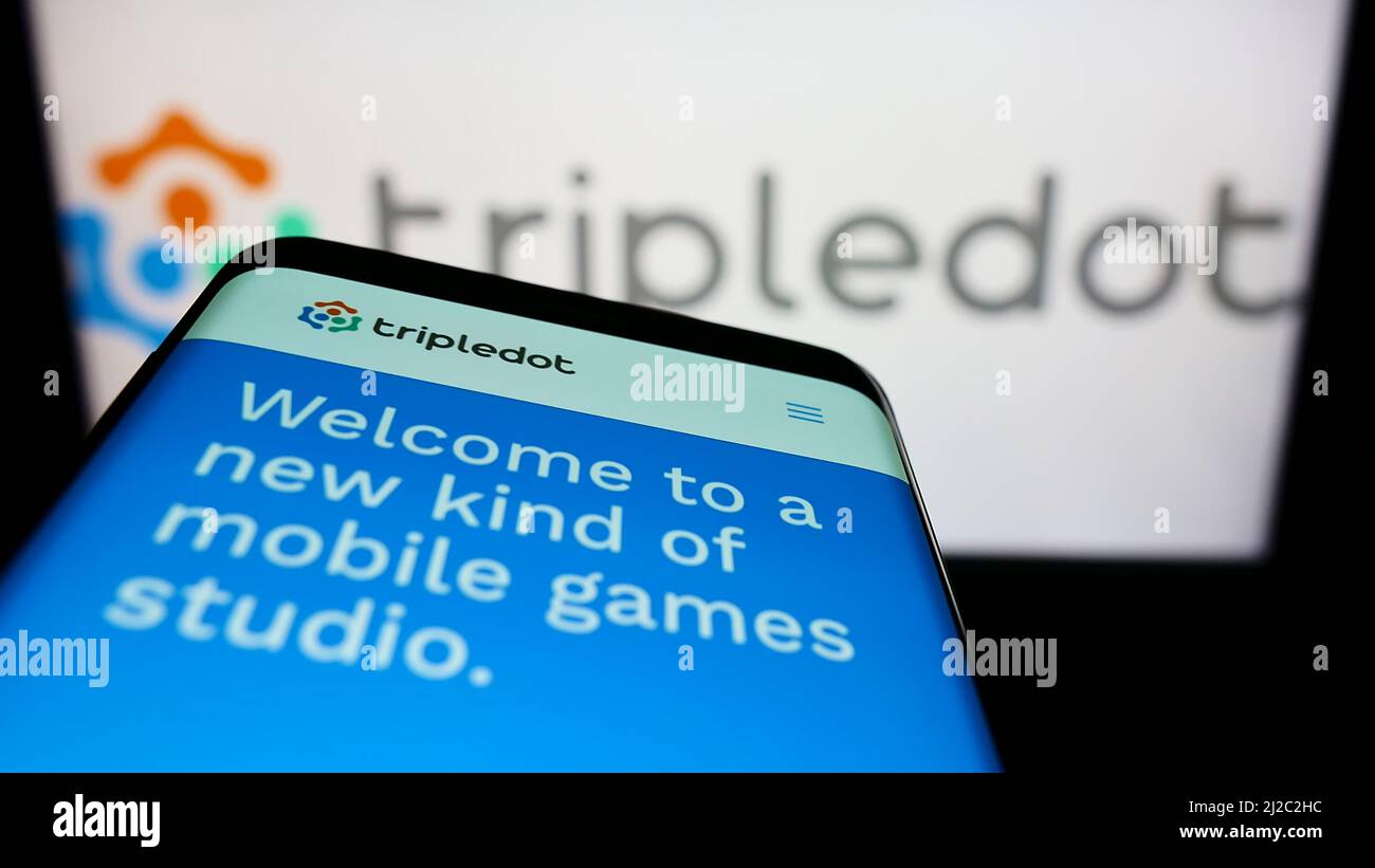 Mobile phone with website of British gaming company Tripledot Studios Limited on screen in front ...
