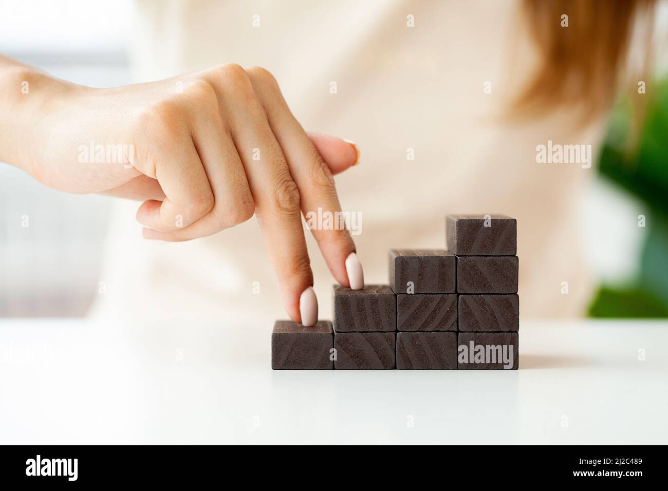 Hand stacking wooden black blocks for in shape of staircase Stock Photo ...