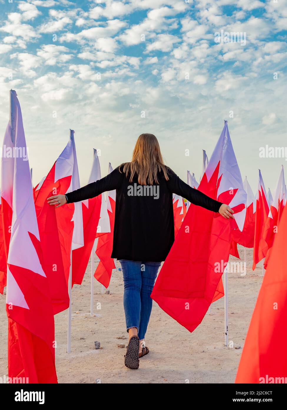 A vertical shot of a female walking by Bahrain Flag display for Bahrain ...