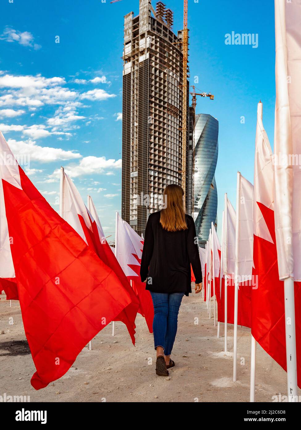 A vertical shot of a female walking by Bahrain Flag display for Bahrain ...