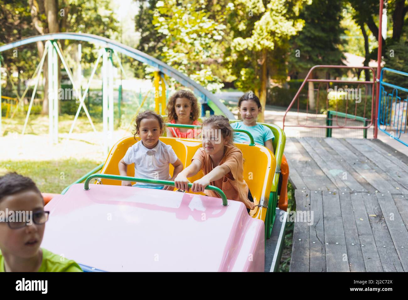 The happy kids on a roller coaster in the amusement park Stock Photo ...