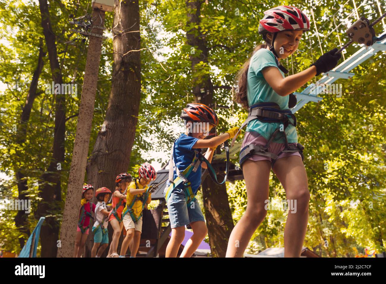 Back view of the children who are overcoming obstacles in the rope park ...