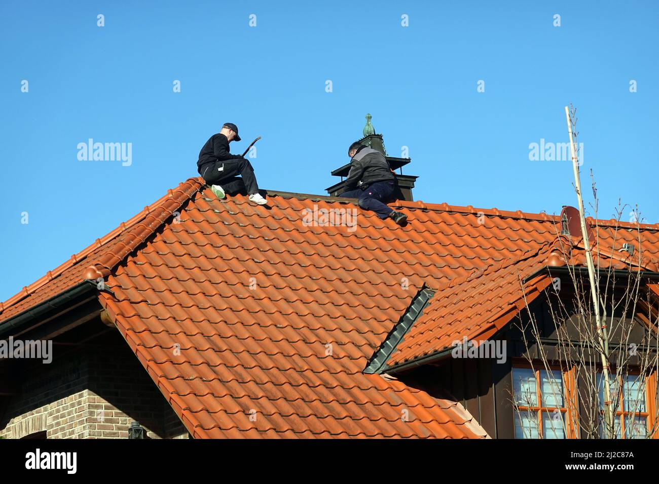 zwei Dachdecker arbeiten am First eine Daches Stock Photo - Alamy