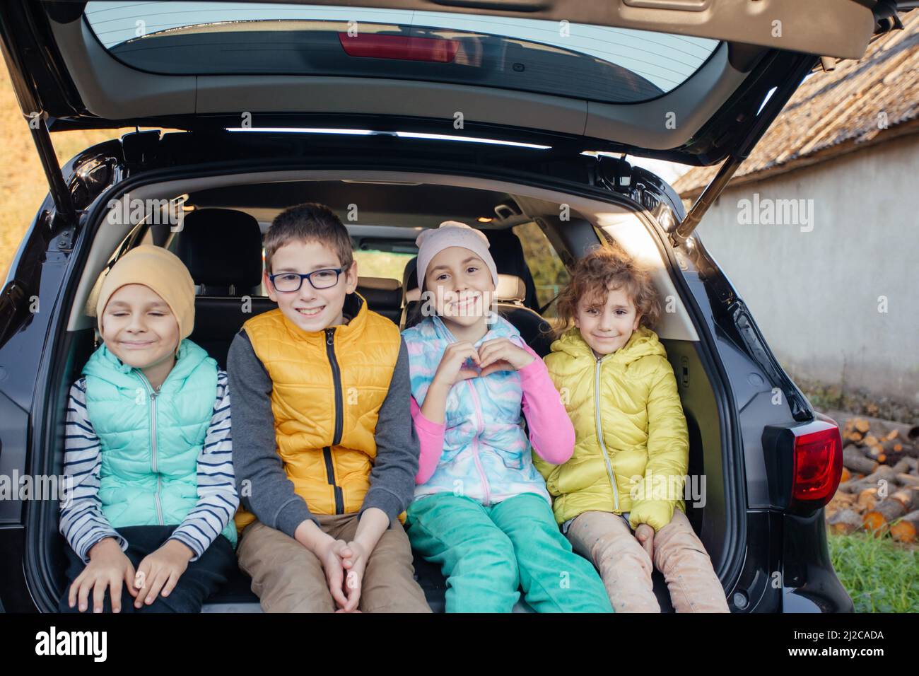Group of children sitting in hatchback car with mountain background ...