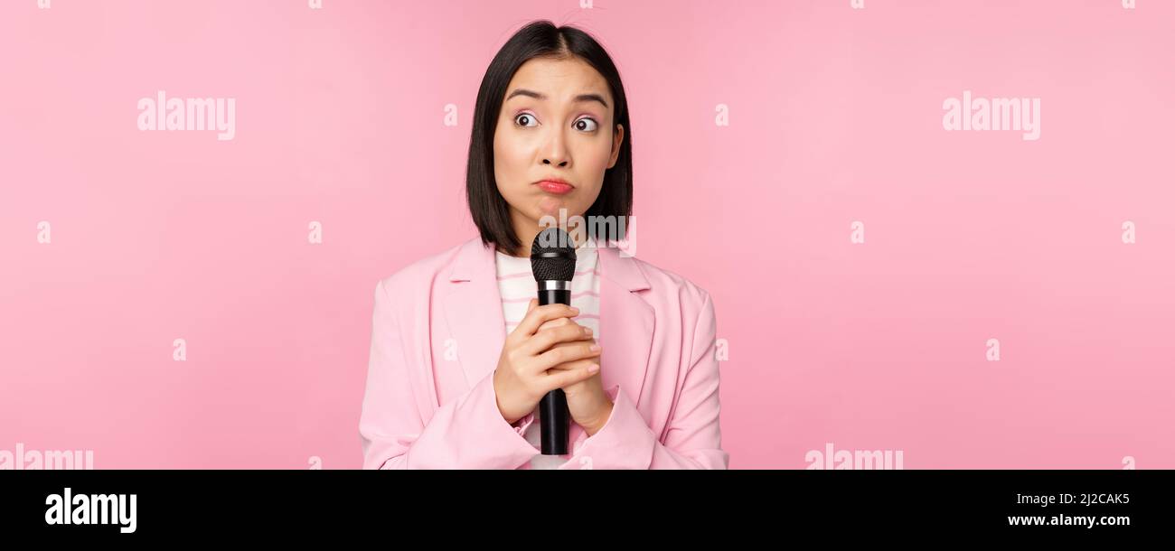 Nervous female entrepreneur giving speech with microphone, holding mic ...