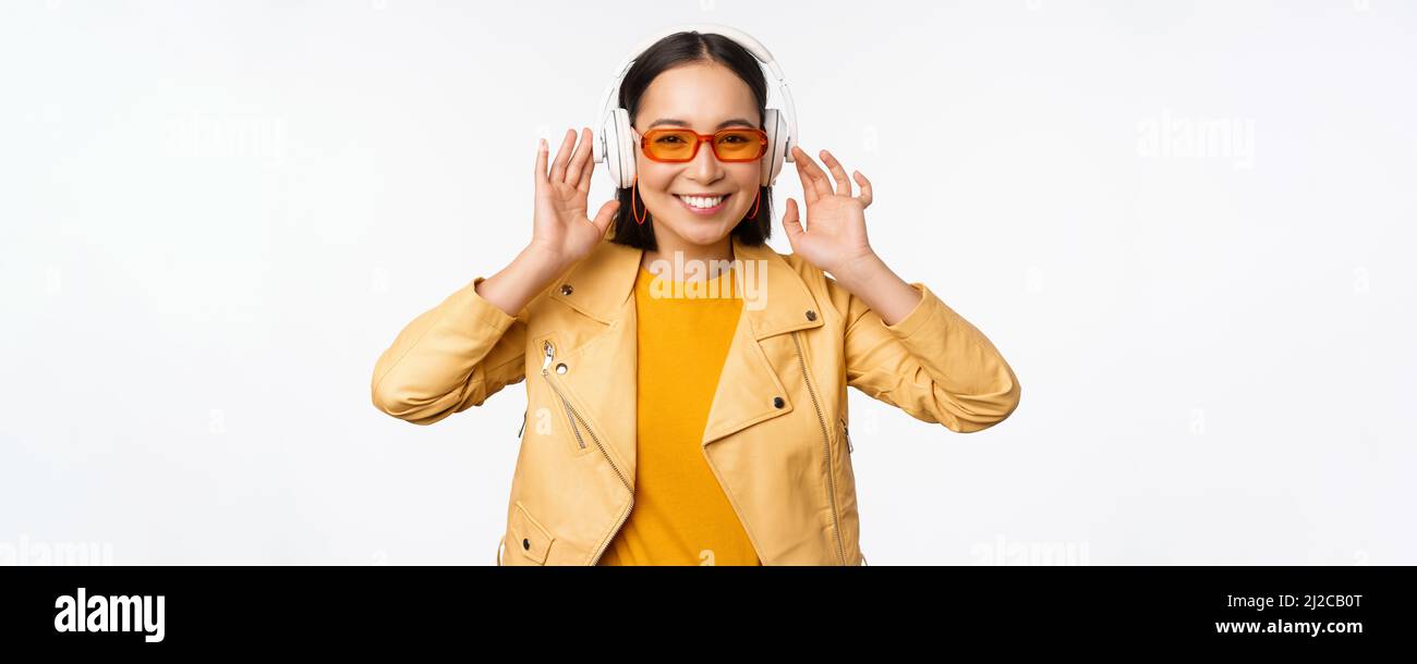 Beautiful asian girl, laughing happy, listening music in headphones ...