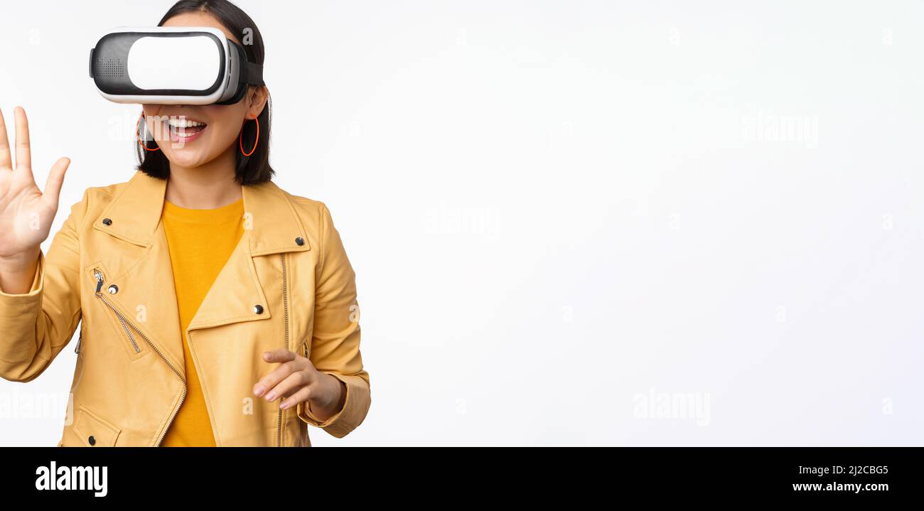 Happy asian girl in VR headset, saying hello in virtual reality chat ...