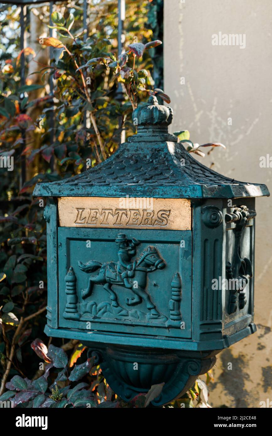 An ancient cast iron mailbox standing on a sidewalk with the word ...