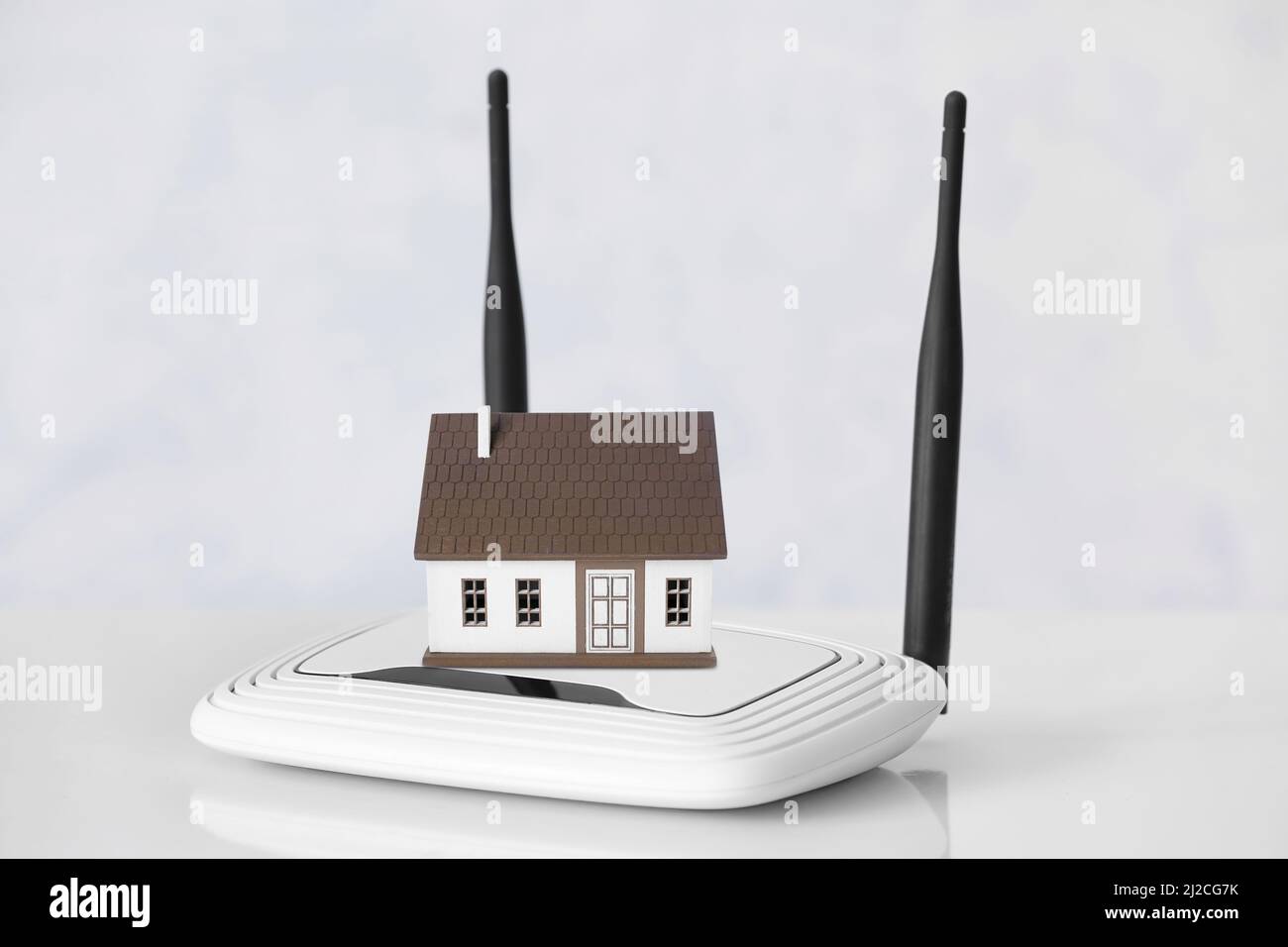 Modern wi-fi router and figure of house on light background Stock Photo ...