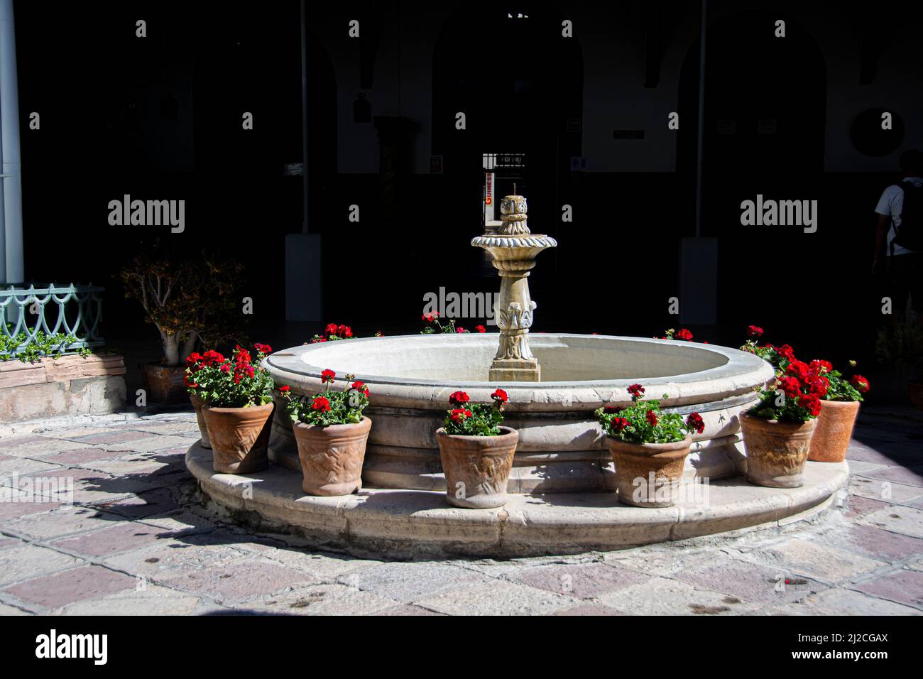 A Spanish-style water fountain lined with several terra cotta pots ...