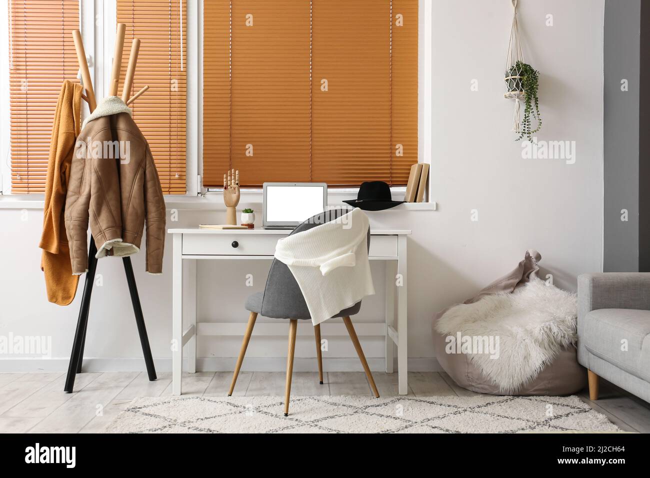 Interior of modern room with workplace and coat rack near window Stock ...