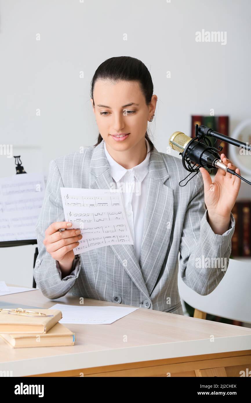Young woman with note sheet recording her voice in room Stock Photo - Alamy