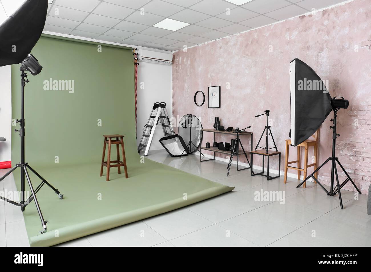 Lighting equipment, green cyclorama and stool in modern photo studio ...