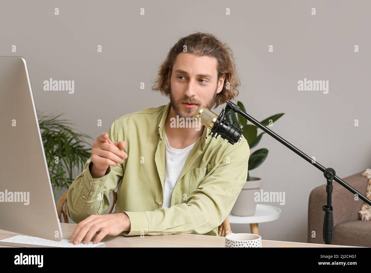 Male blogger using computer and microphone at home Stock Photo - Alamy