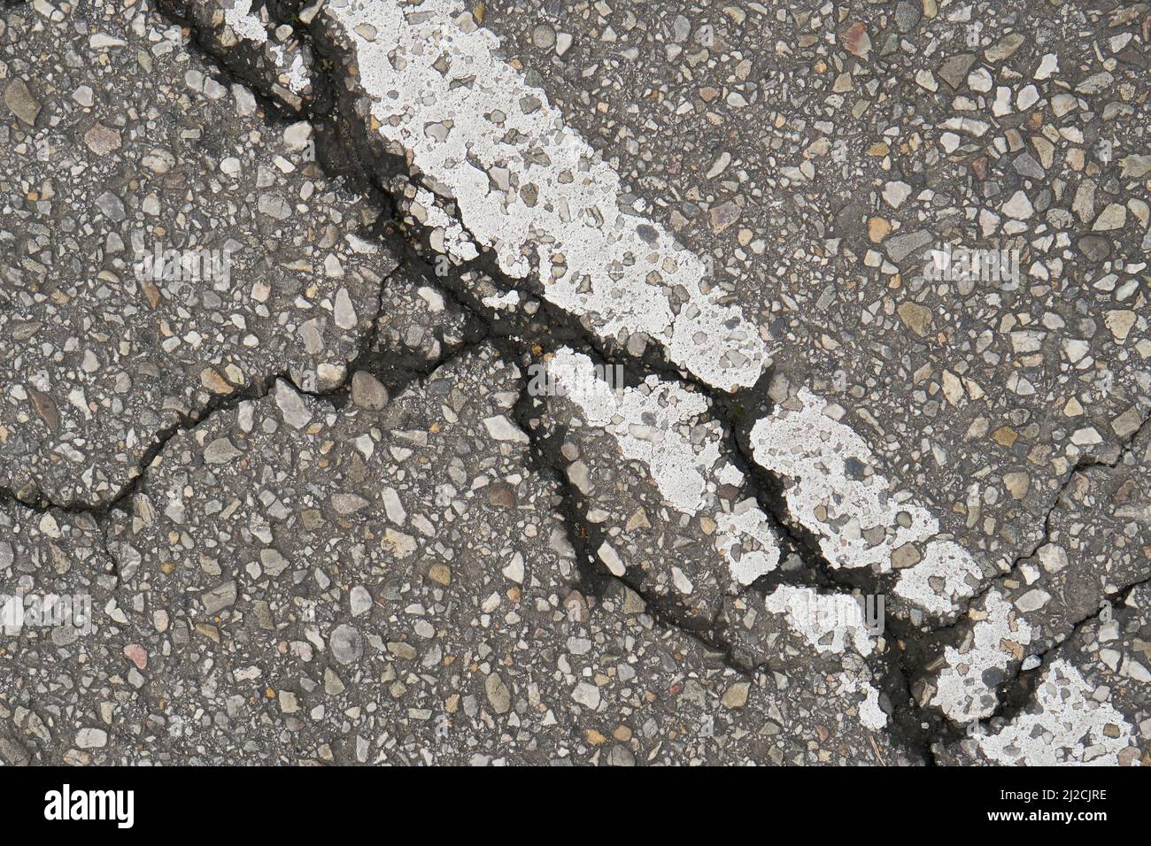 Old damaged cracked asphalt road section with old paint road marking ...