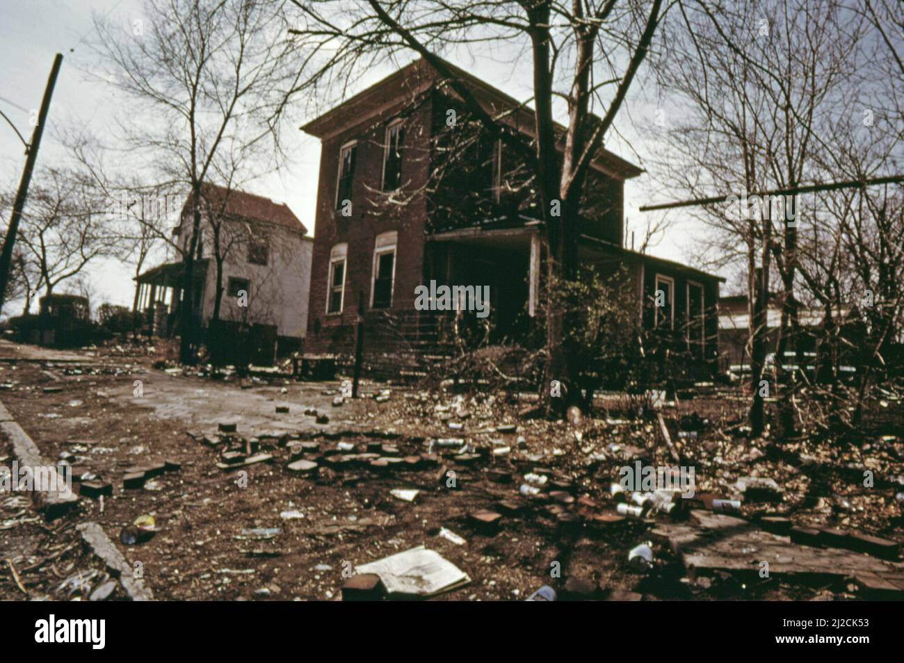 Trash litters the area around the empty brick house vacated by a family ...