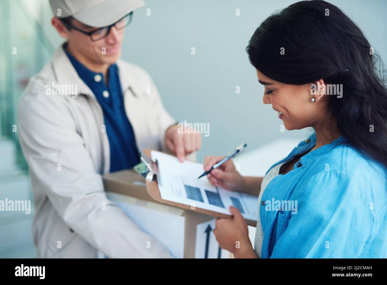 Please sign right here. Shot of a young woman signing for a delivery ...