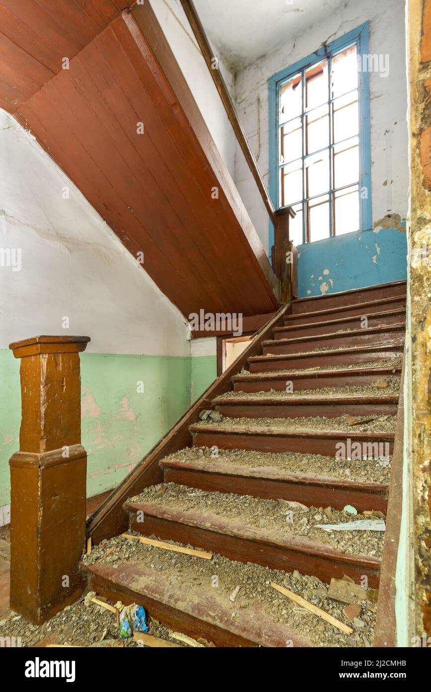 Bottom view of a wooden staircase and a window with broken glass of an ...