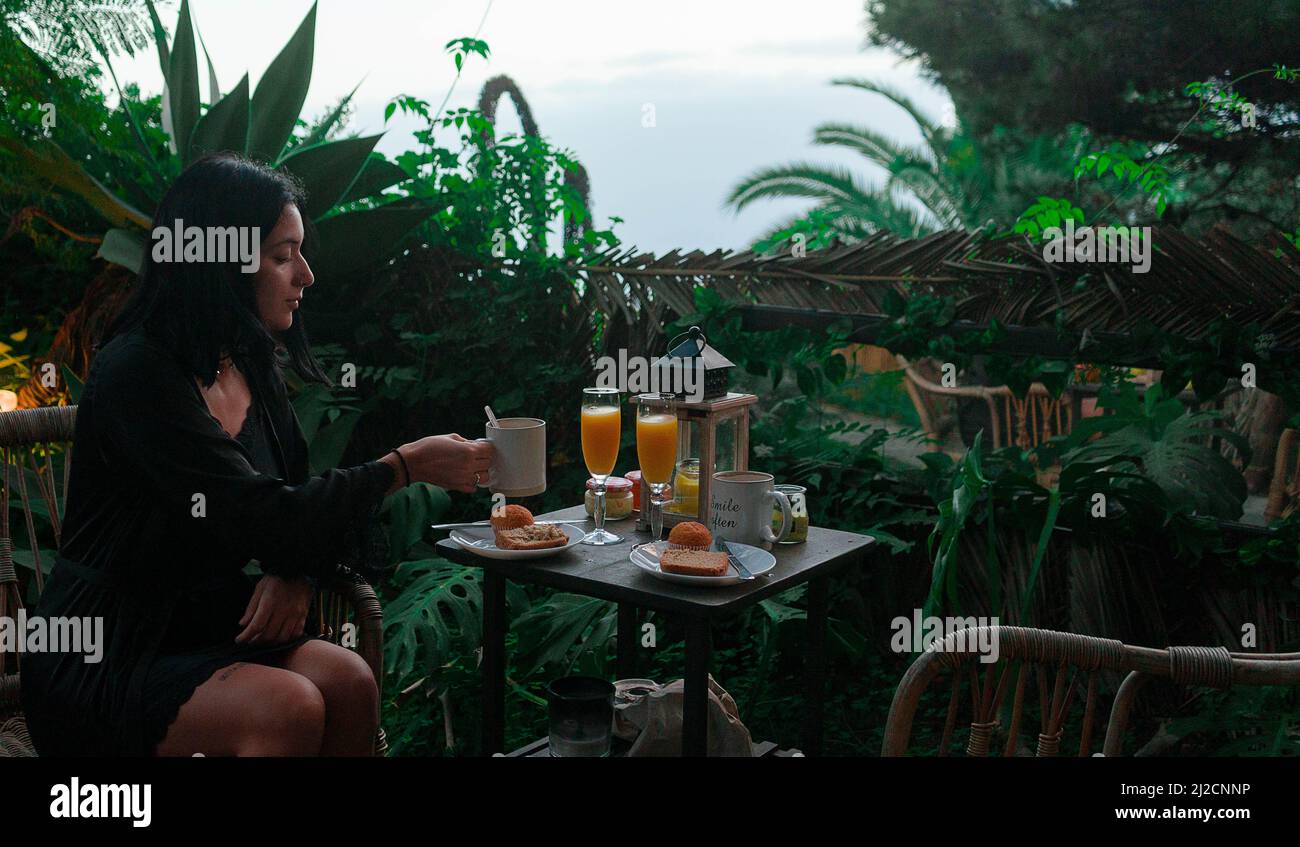 A side view of a young beautiful Spanish woman drinking tea while ...