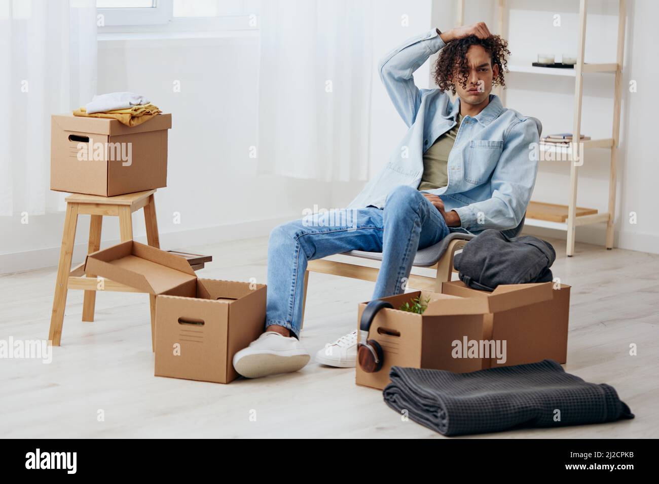 A young man cardboard boxes in the room unpacking sorting things out ...