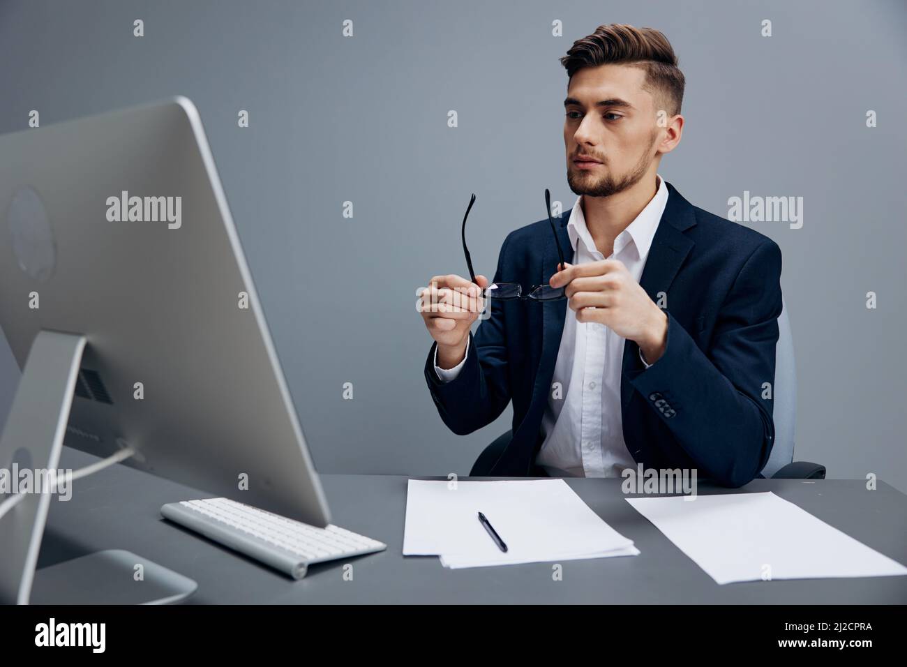 businessmen wearing glasses works in front of a computer Gray background Stock Photo - Alamy