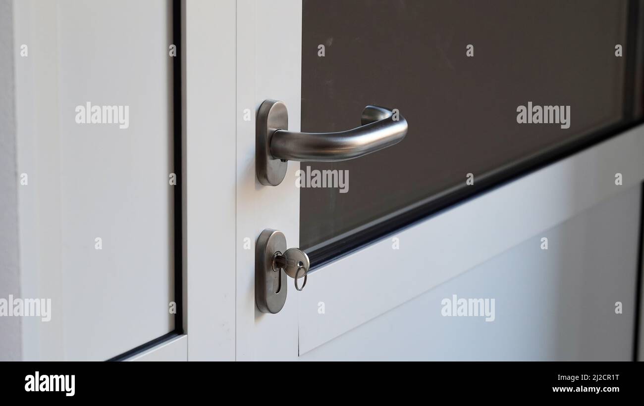 Close-up of a metal key in the keyhole in a plastic white door, the ...