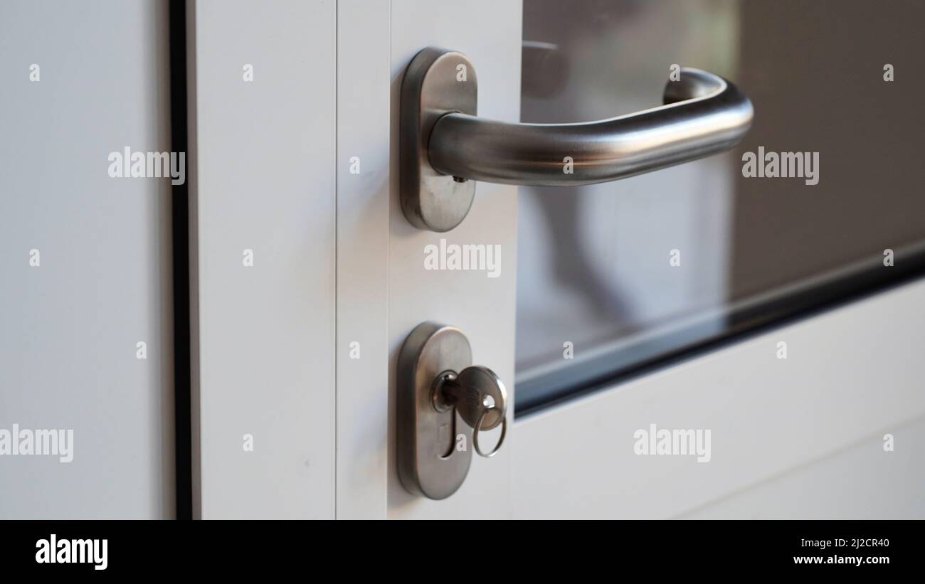 Close-up of a metal key in the keyhole in a plastic white door, the ...