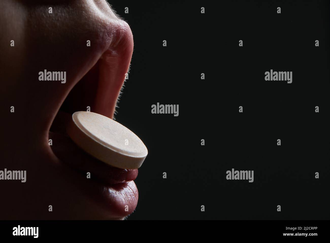 Close up of face of young woman taking drug. The drug addict is ...