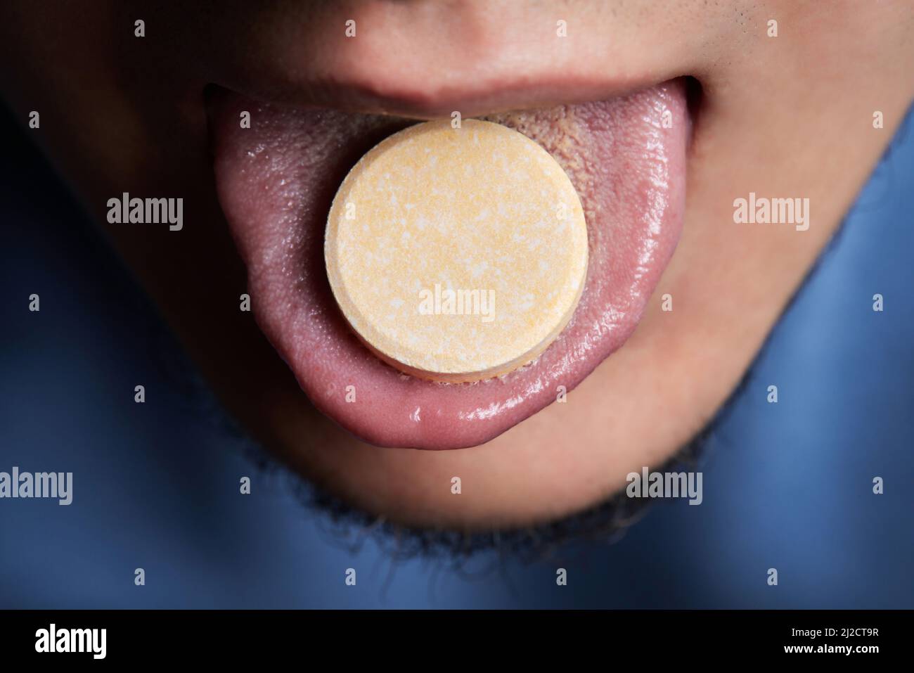 Man taking pill, mouth open with tongue sticking out Stock Photo - Alamy