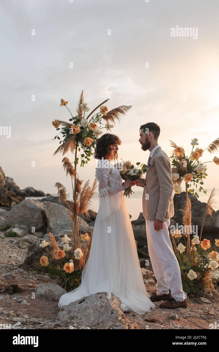 Wedding on the sunset with live floristry. Bride and groom in boho ...