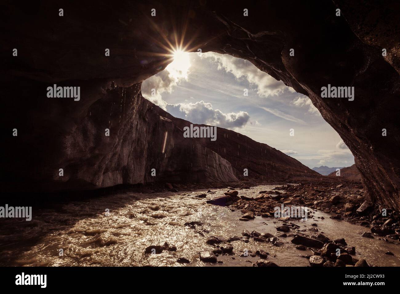 Glacial stream that coming out of a cave carved into a glacier ice at ...