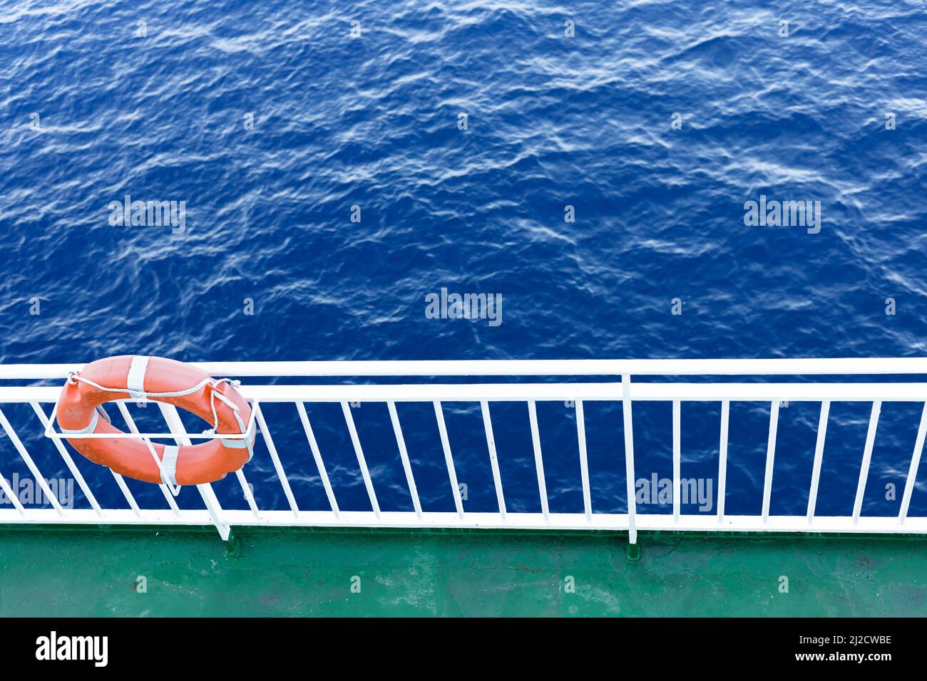 Lifesaver hanging in the guardrail of a ship with the blue water as ...