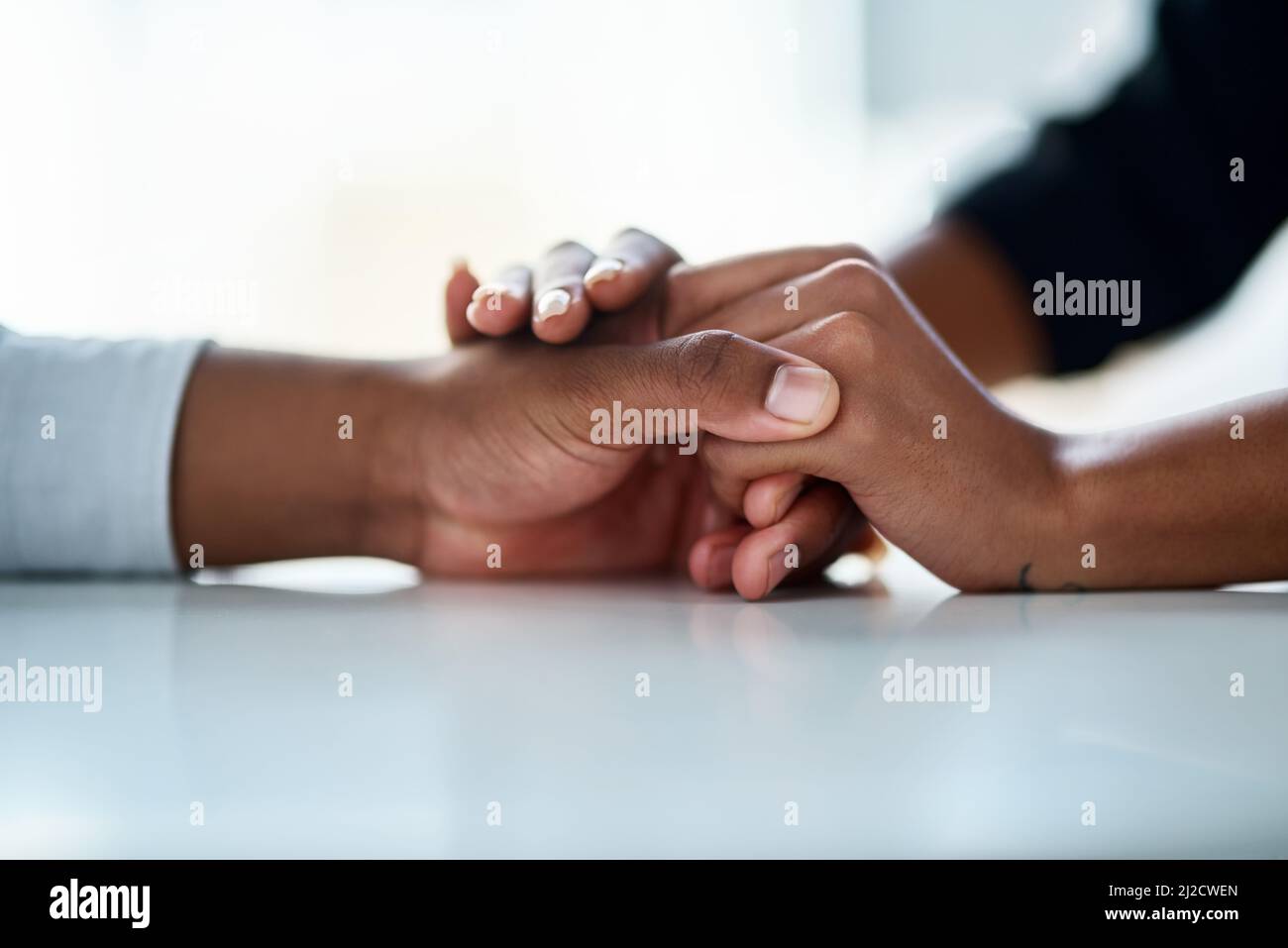 You are not alon. Cropped of two unrecognizable people holding hands ...