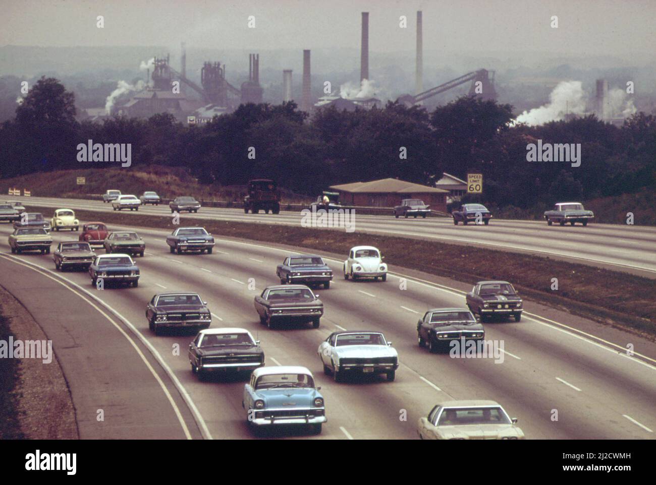 Cars driving on a highway with smoke-belching chimneys and smog ...