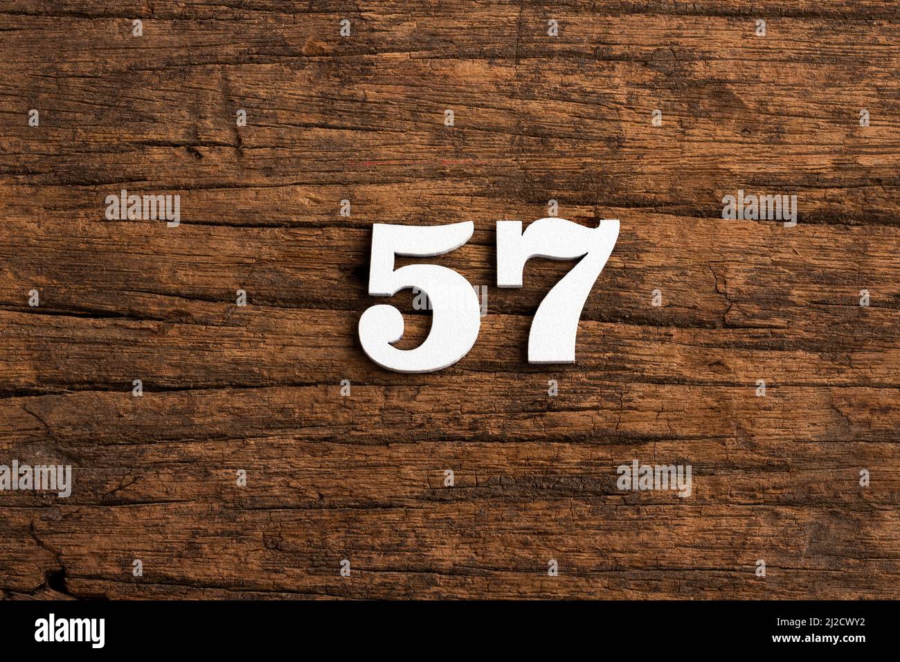 Number 57 - piece on rustic wood background Stock Photo - Alamy