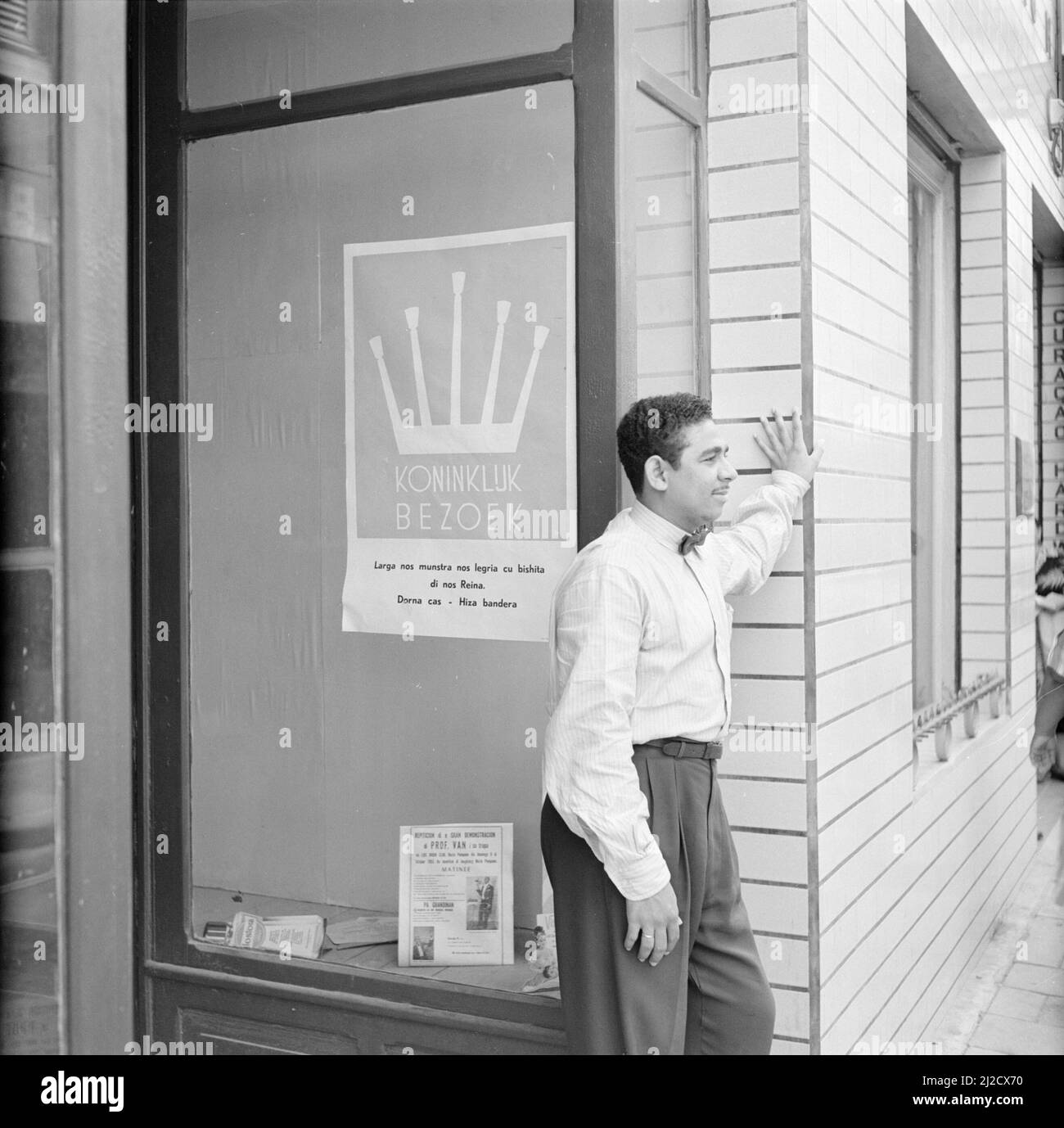 A shopkeeper at a shop window with a poster of the royal visit in ...