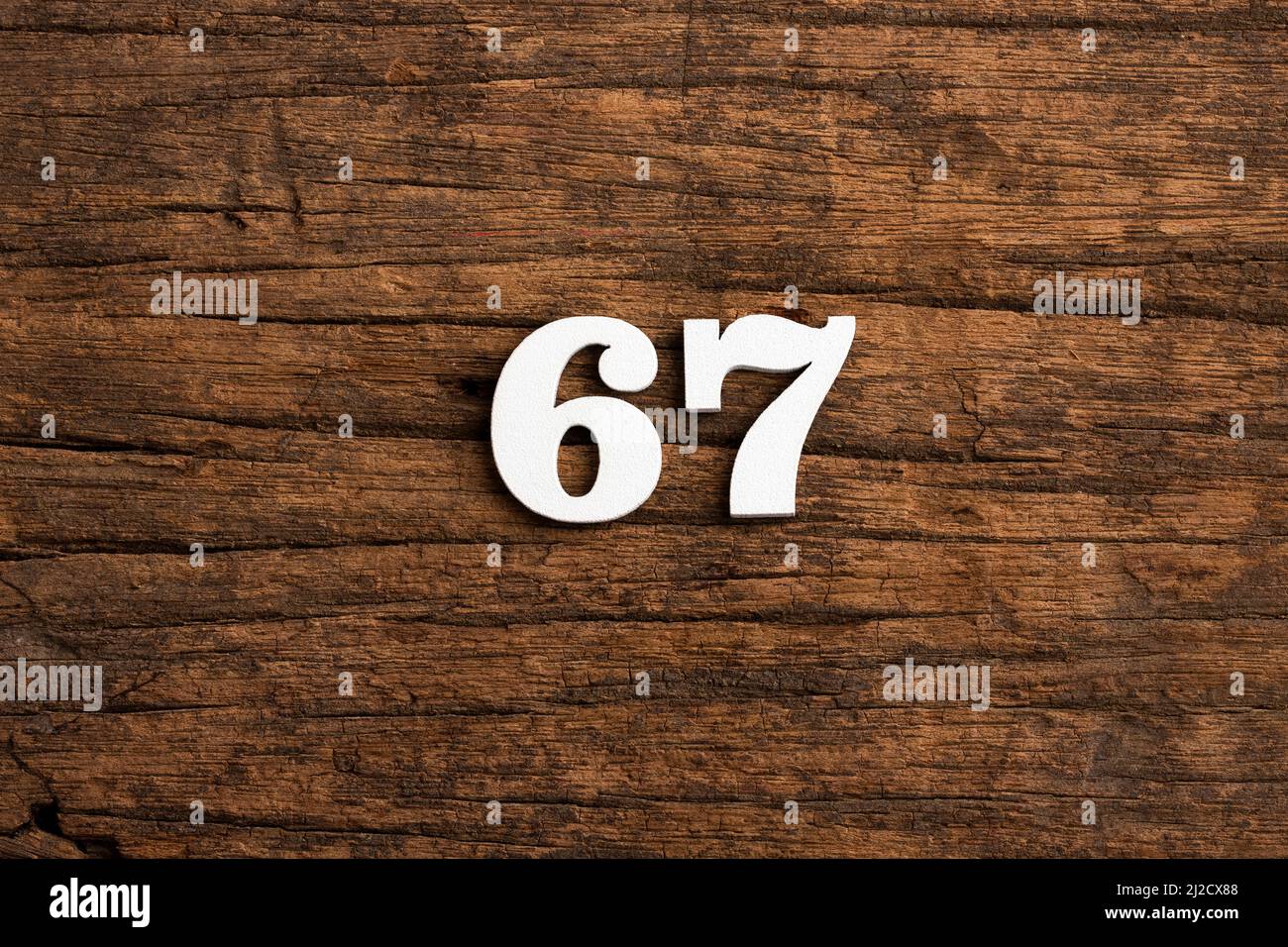 Number 67 - piece on rustic wood background Stock Photo - Alamy