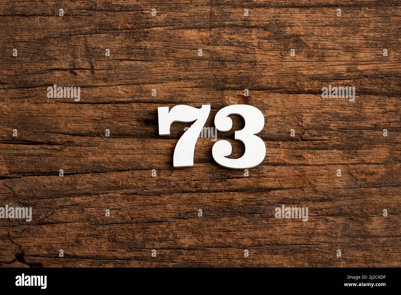 Number 73 - piece on rustic wood background Stock Photo - Alamy