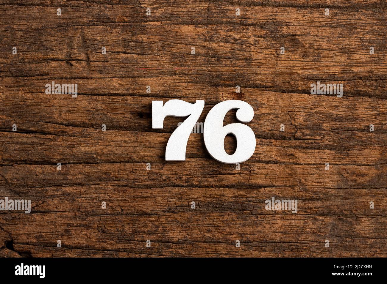 Number 76 in wood, isolated on rustic background Stock Photo - Alamy