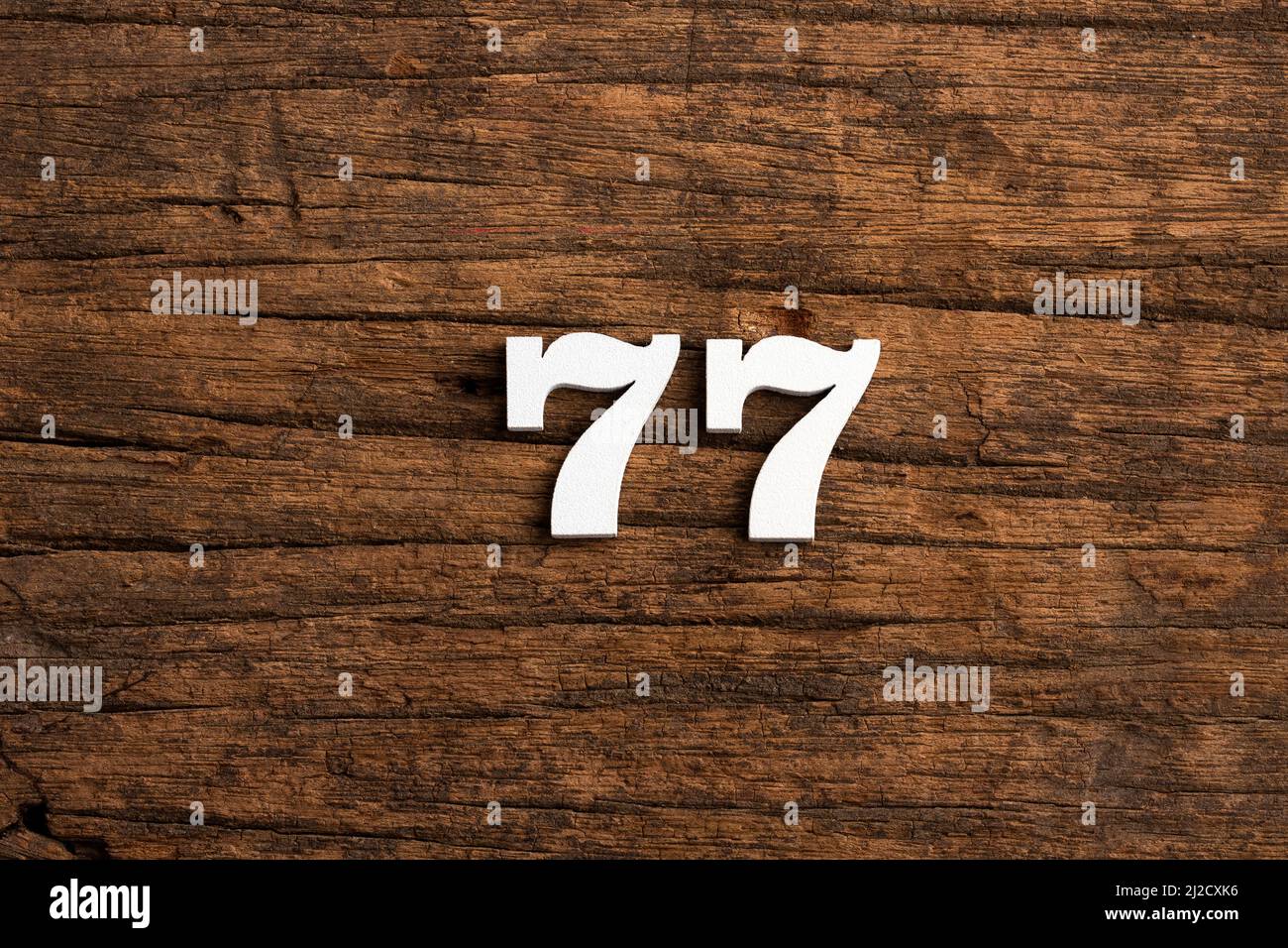 Number 77 - piece on rustic wood background Stock Photo - Alamy