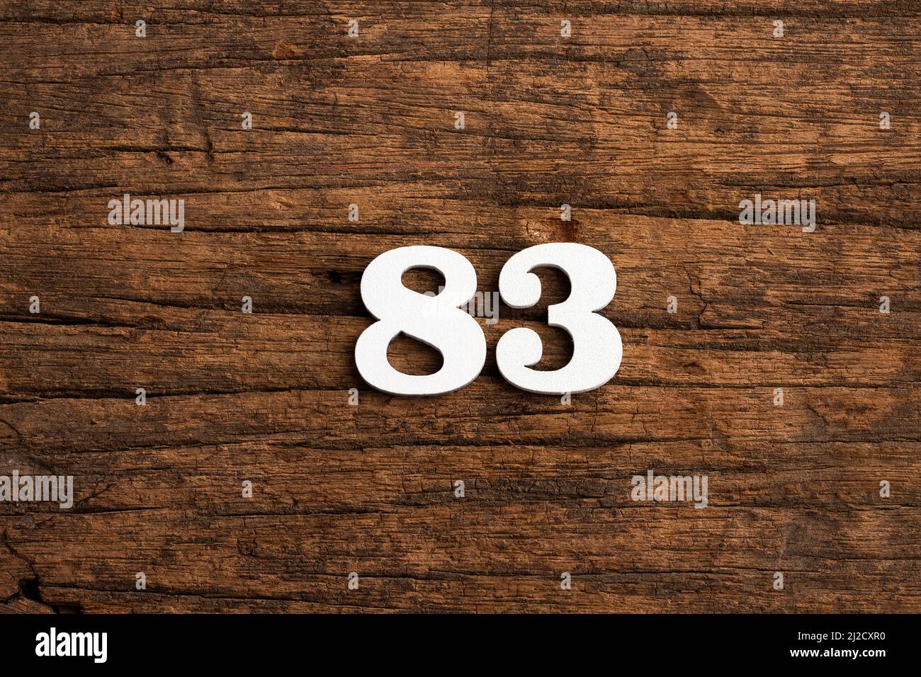 Number 83 - piece on rustic wood background Stock Photo - Alamy