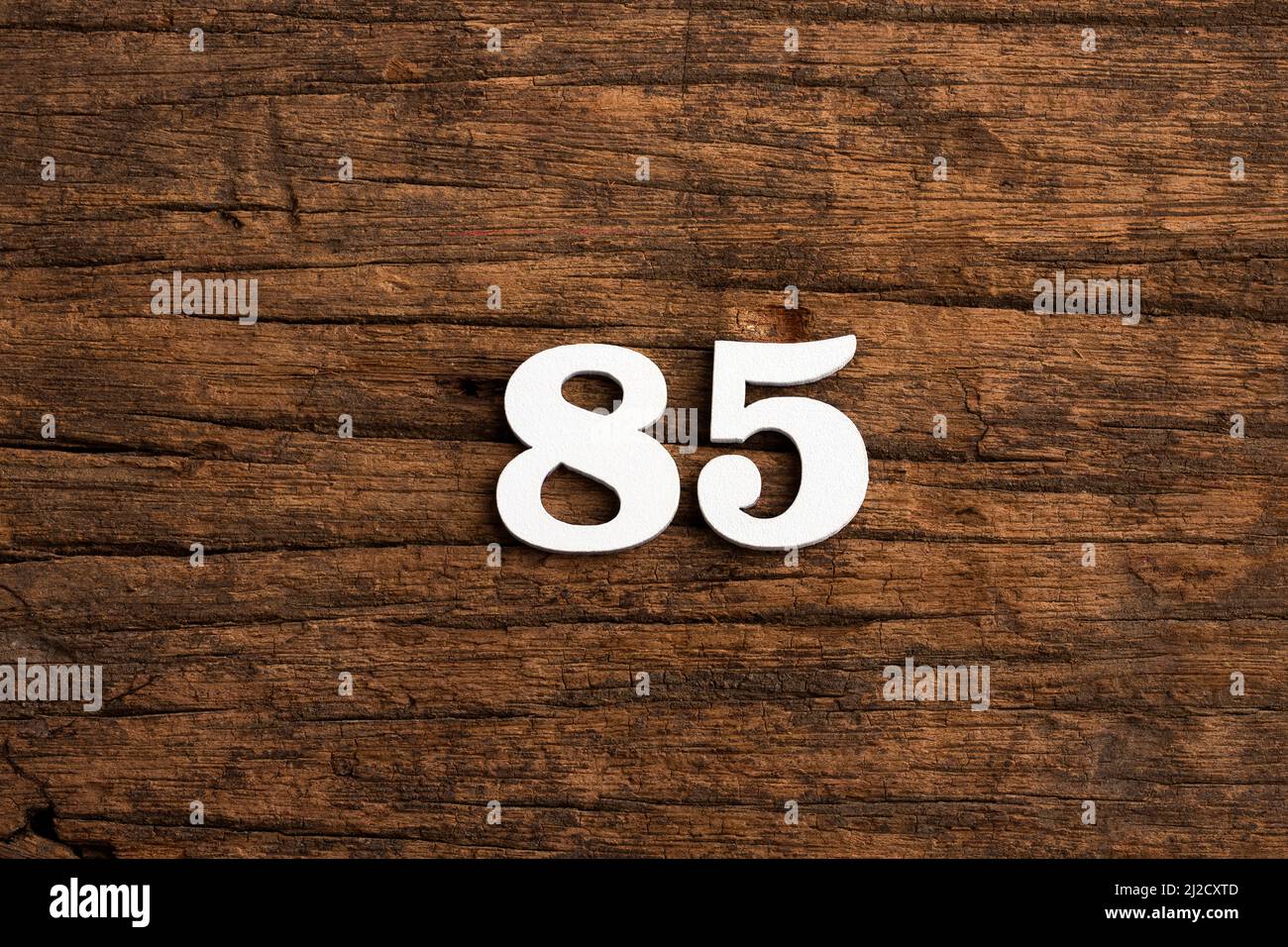 Number 85 - piece on rustic wood background Stock Photo - Alamy