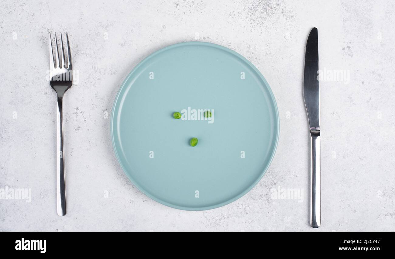 One single pea on a plate, hand with tape measure and fork, diet and ...