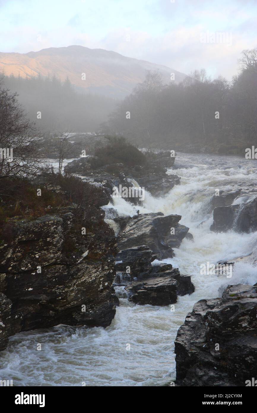 A natural view of rushing water flowing downstream on a rocky river ...